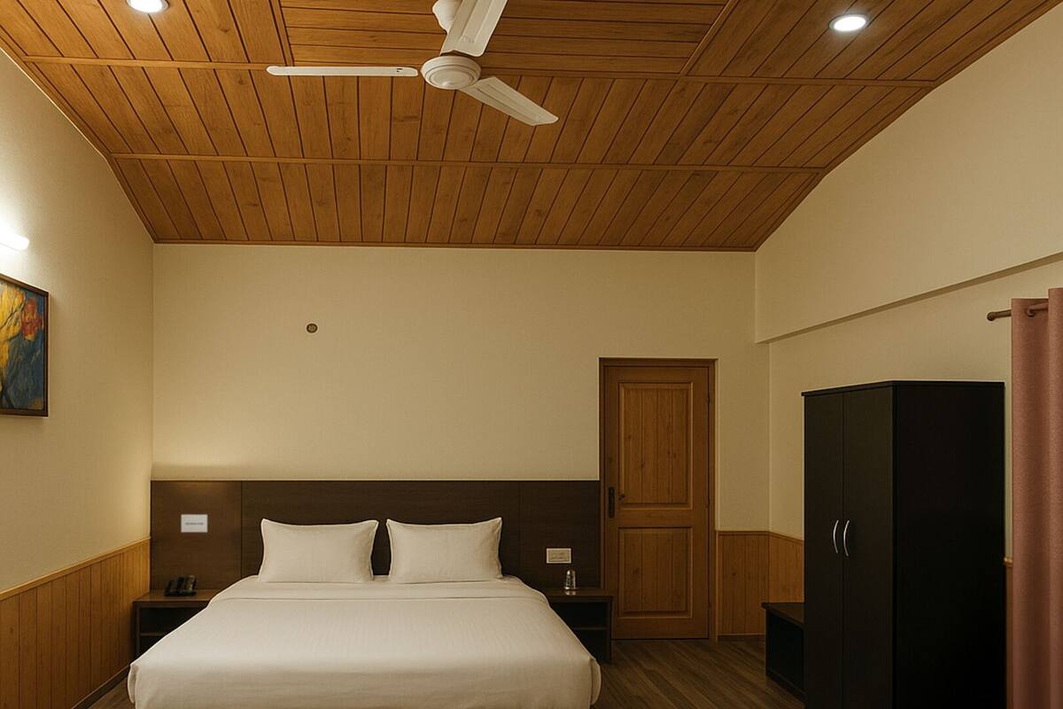 Quarto de hotel com teto de madeira, cama com roupa de cama branca, mesa de cabeceira, guarda-roupa e uma porta.