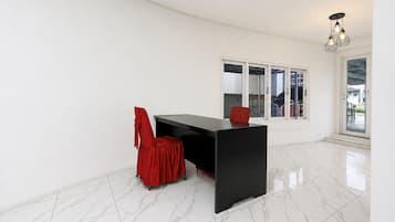 Quarto moderno com escrivaninha preta, duas cadeiras vermelhas, uma janela grande e um lustre.