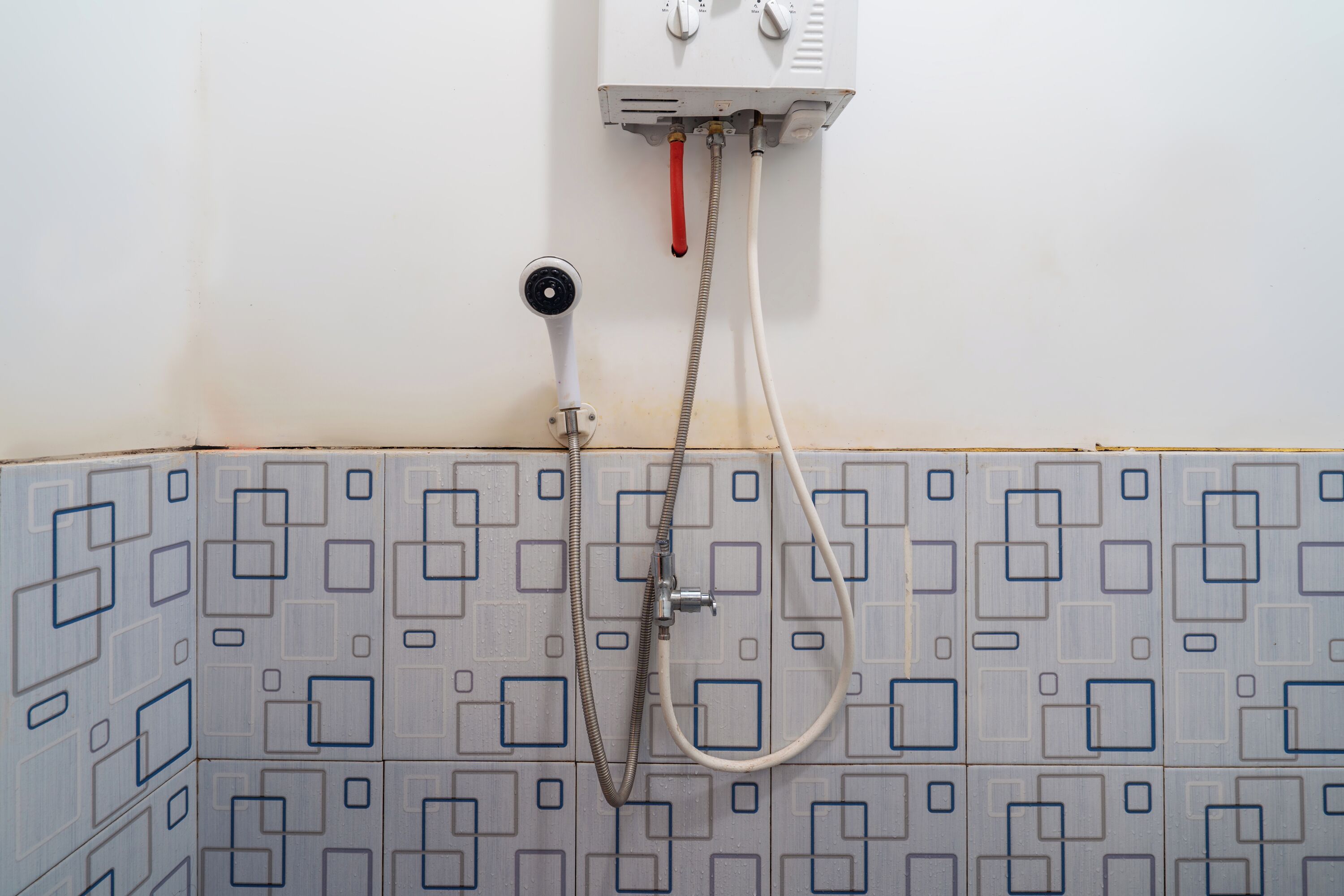 Casa de banho com chuveiro, aquecedor na parede e sanita.