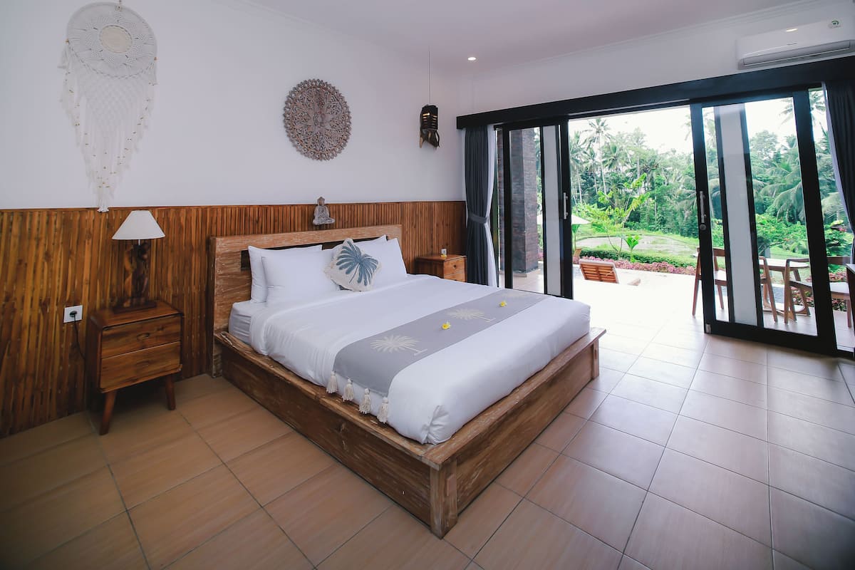 Quarto com cama de madeira, mesa de cabeceira, decoração na parede e vista para o exterior.