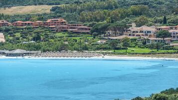 Um resort costeiro com vários edifícios, uma praia e vegetação exuberante.