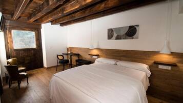 Quarto com teto de madeira, uma cama, uma escrivaninha, uma cadeira e uma janela.
