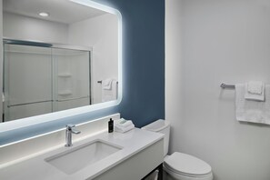 Uma casa de banho moderna com um espelho grande, uma pia e uma sanita.