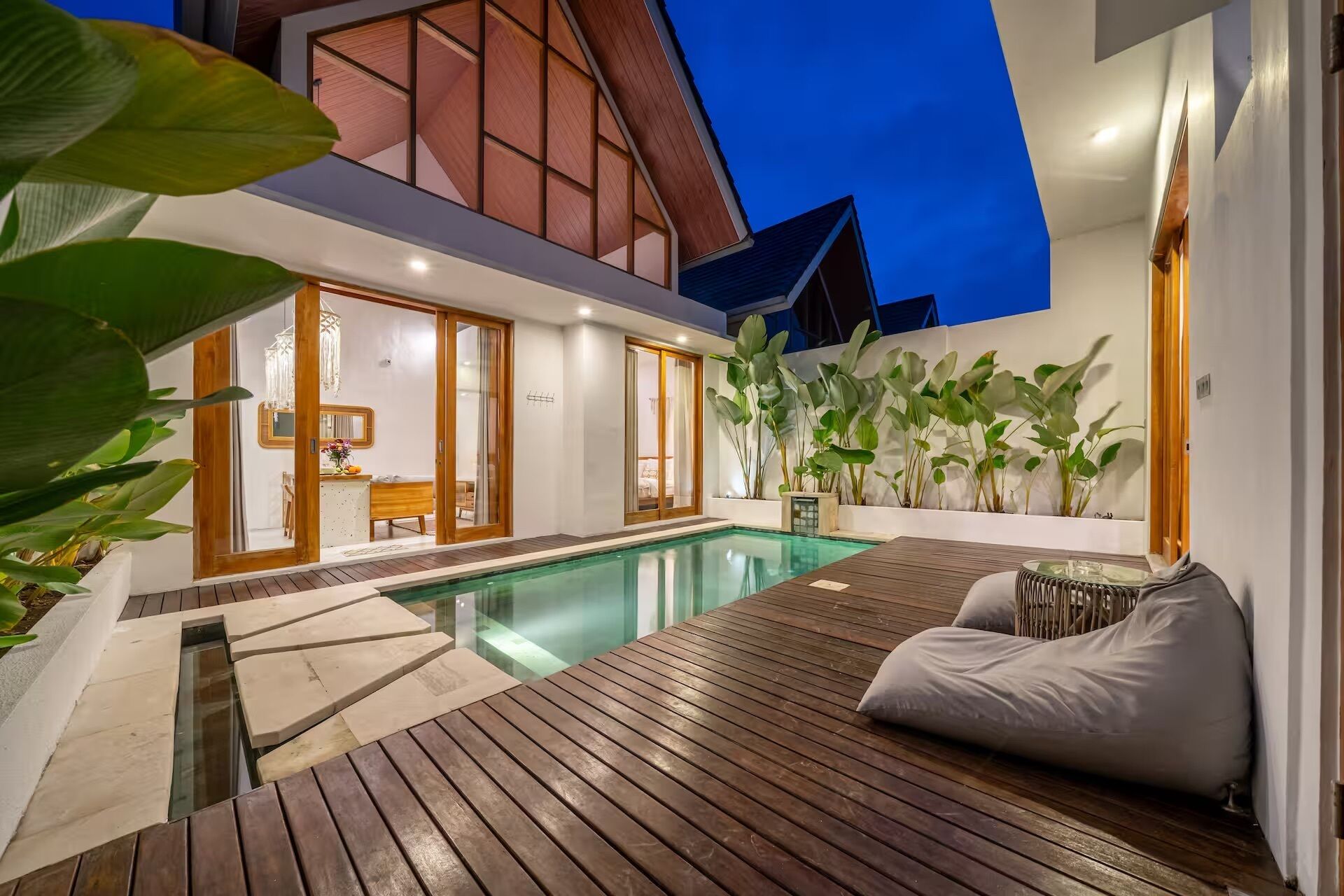 Uma casa moderna com piscina, deck de madeira e área de estar interna.