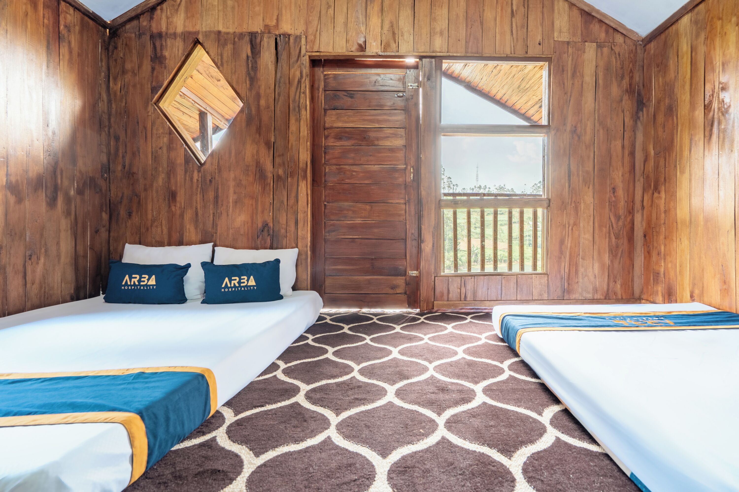 Um quarto de madeira com duas camas, uma janela e uma porta.