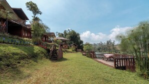 Resort com várias cabanas de madeira, um caminho gramado e uma ponte de madeira que leva a um cais.