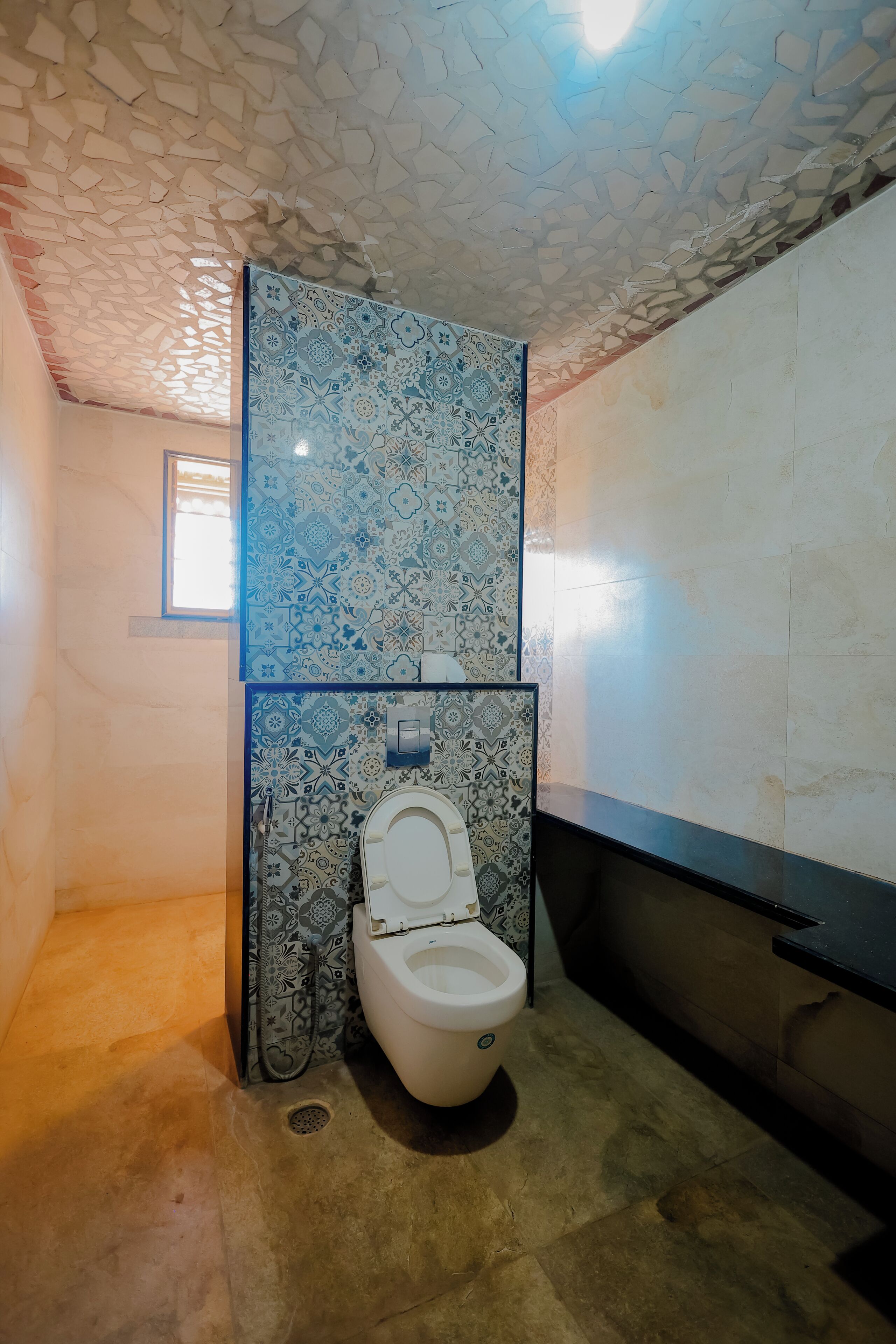 Casa de banho com parede revestida de azulejos estampados, sanita e banheira.