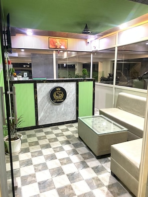 Uma área de recepção com piso xadrez, um balcão de atendimento com um logotipo e disposição de assentos.