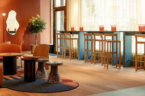 Um interior moderno com cadeiras de madeira, uma mesa redonda, uma pequena planta em vaso e um espelho na parede.
