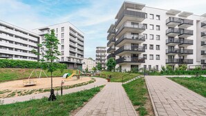 Um edifício residencial com várias varandas, um parquinho e um caminho pavimentado.
