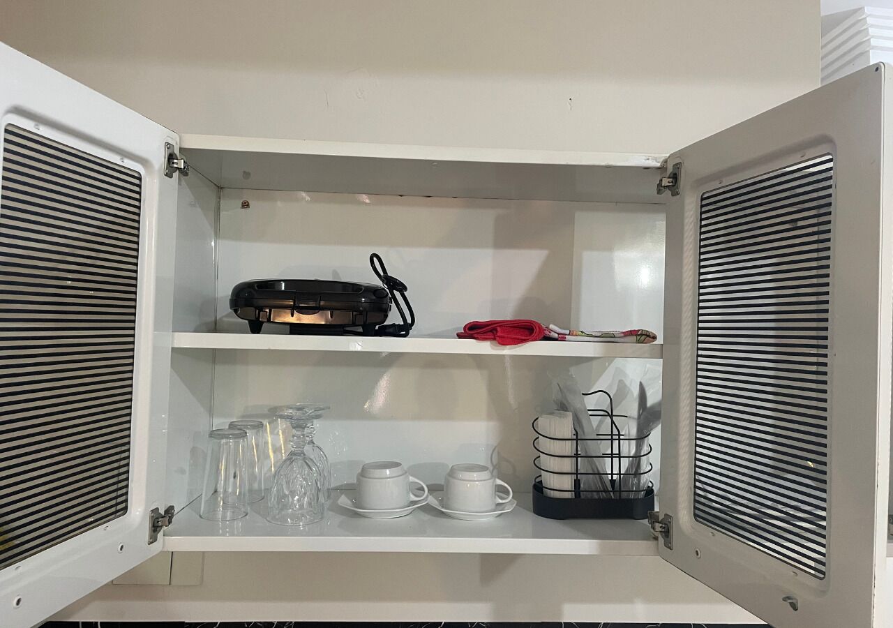 Um armário de cozinha com um micro-ondas, uma faca de cabo vermelho e um porta-utensílios.
