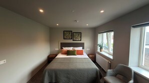 Quarto com cama, cadeira, janela e radiador.