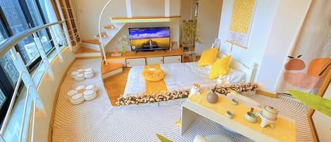 Uma sala de estar moderna com sofá, mesa de centro e televisão. Escada leva a um andar superior.