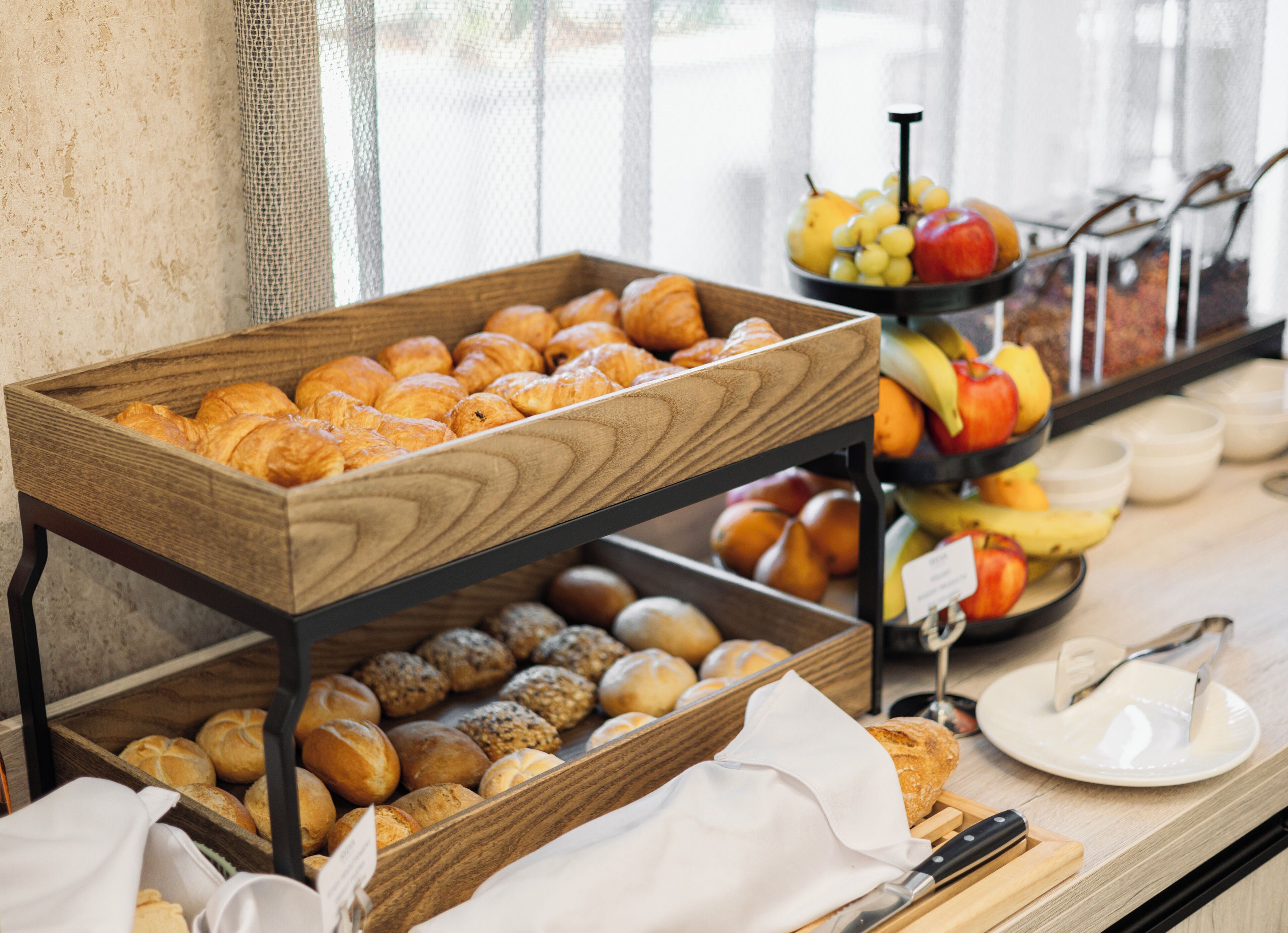 Um buffet de café da manhã com diversos pães e frutas.
