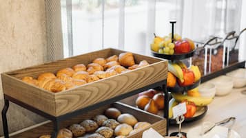 Um buffet de café da manhã com diversos pães e frutas.