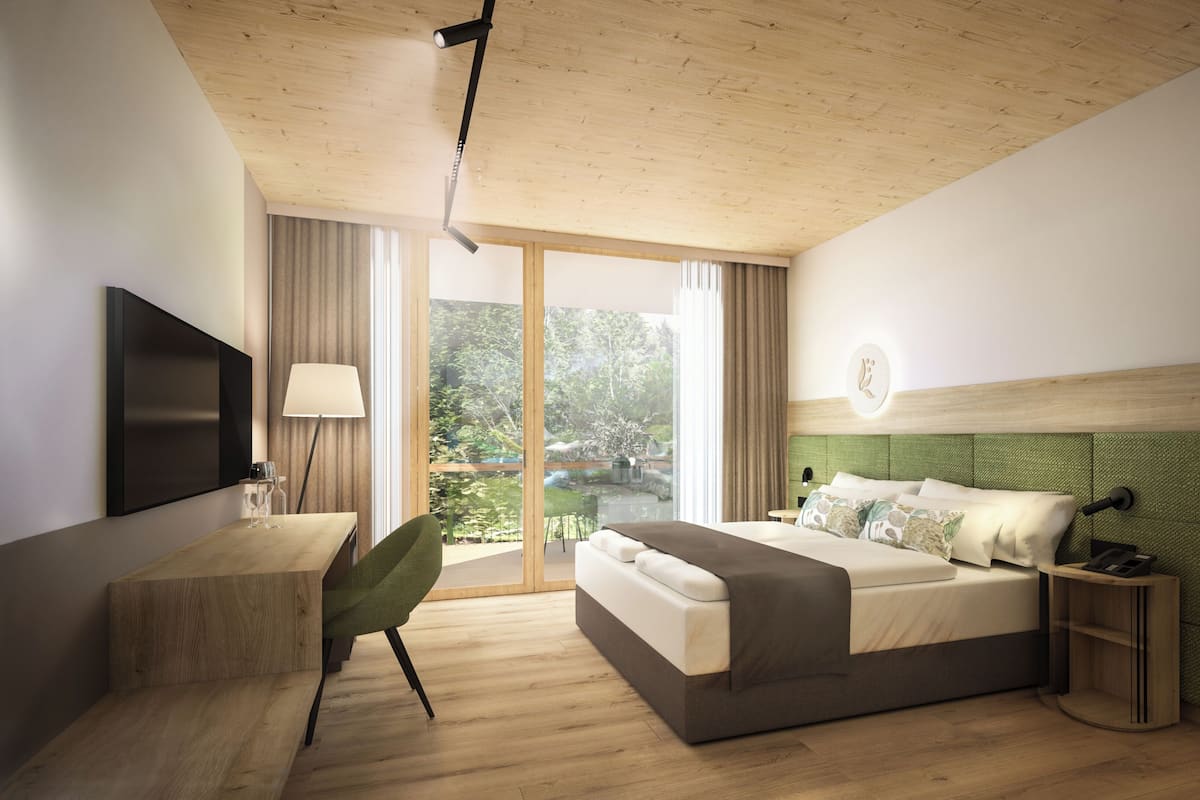 Quarto moderno com cama, escrivaninha, cadeira e televisão.