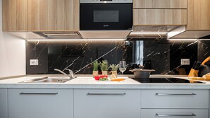 Cozinha moderna com micro-ondas preto, pia de aço inoxidável e painel de fundo de mármore.