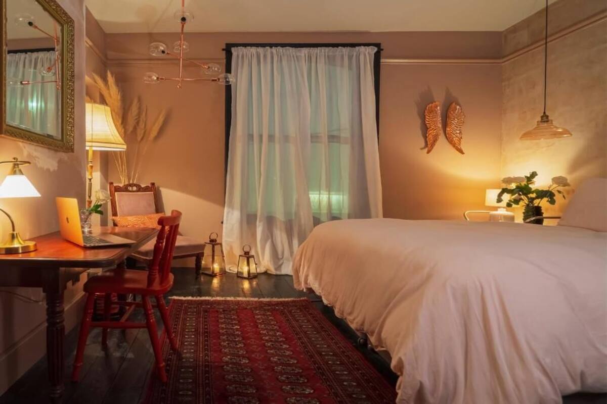 Quarto com cama, escrivaninha, cadeira, luminária e objetos decorativos.