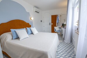 Quarto de hotel com cama, escrivaninha e banheiro.