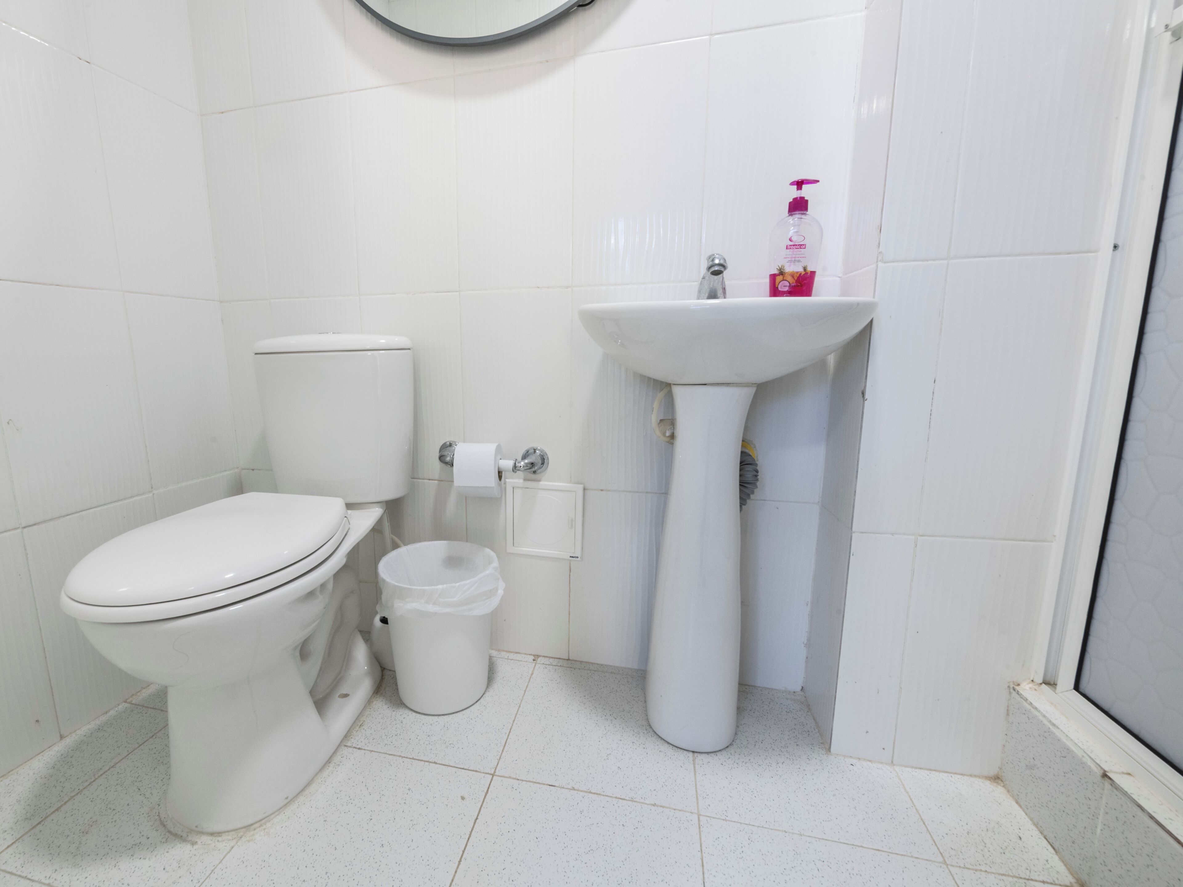 Casa de banho com sanita, lavatório e um contentor de lixo.