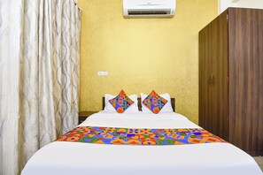 Quarto de hotel com cama, cortinas, ar condicionado e um guarda-roupa.