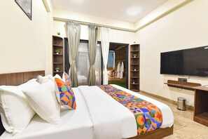 Quarto de hotel com cama, televisão, guarda-roupa e uma pequena planta.