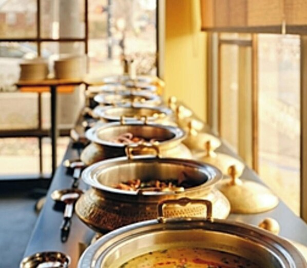 Uma mesa de buffet com vários recipientes de comida.