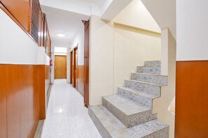 Um corredor com painéis de madeira, escada revestida de azulejos e um extintor de incêndio.