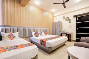Quarto de hotel com duas camas, uma escrivaninha, uma cadeira e um guarda-roupa.