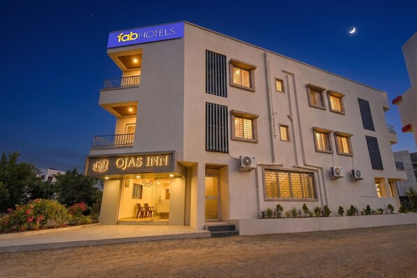 Um hotel moderno com uma placa indicando 'fabHOTELS' e 'OJAS INN' na fachada.