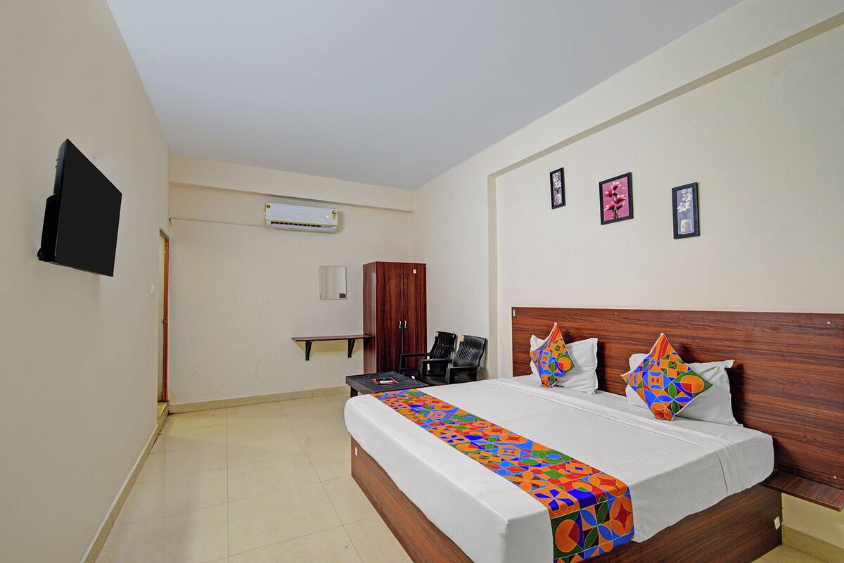 Quarto de hotel com cama, escrivaninha, ar condicionado e guarda-roupa.