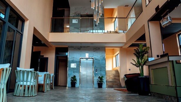 Um hall de hotel com piso de mármore, escada, balcão de recepção e áreas de estar.