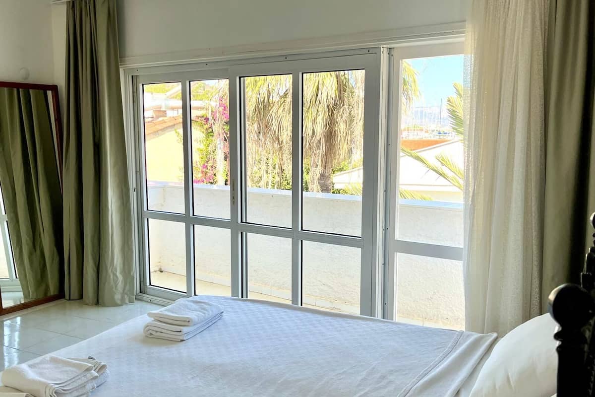 Quarto de hotel com uma cama grande, vista para o exterior e uma janela com cortinas.