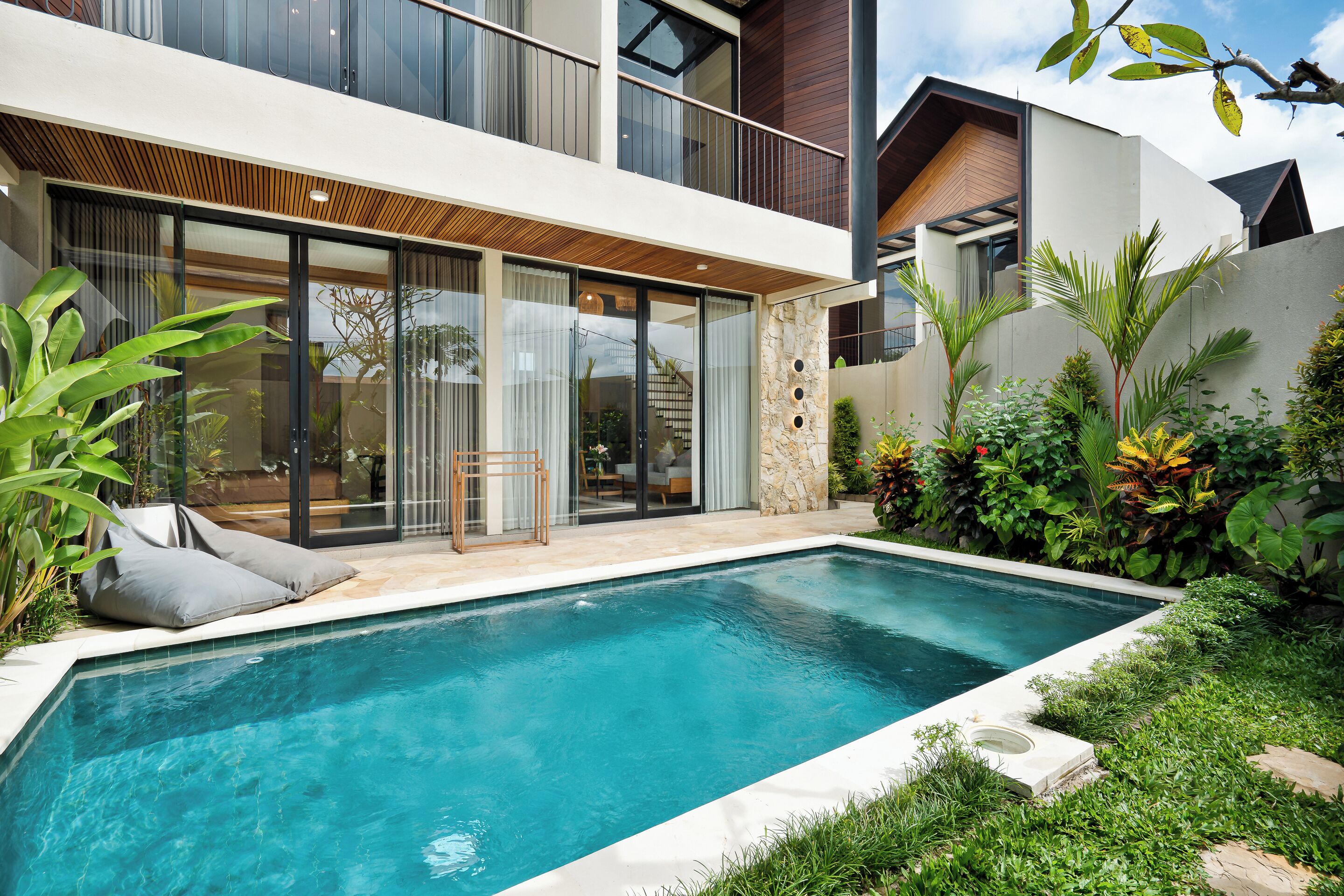 Uma casa moderna com piscina, amplas portas de vidro e um jardim bem cuidado.