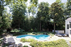 Um quintal com piscina, móveis de jardim e um deck de madeira.