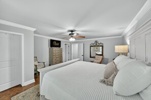 Quarto com cama grande, ventoinha no teto, cômoda, espelho e abajur.