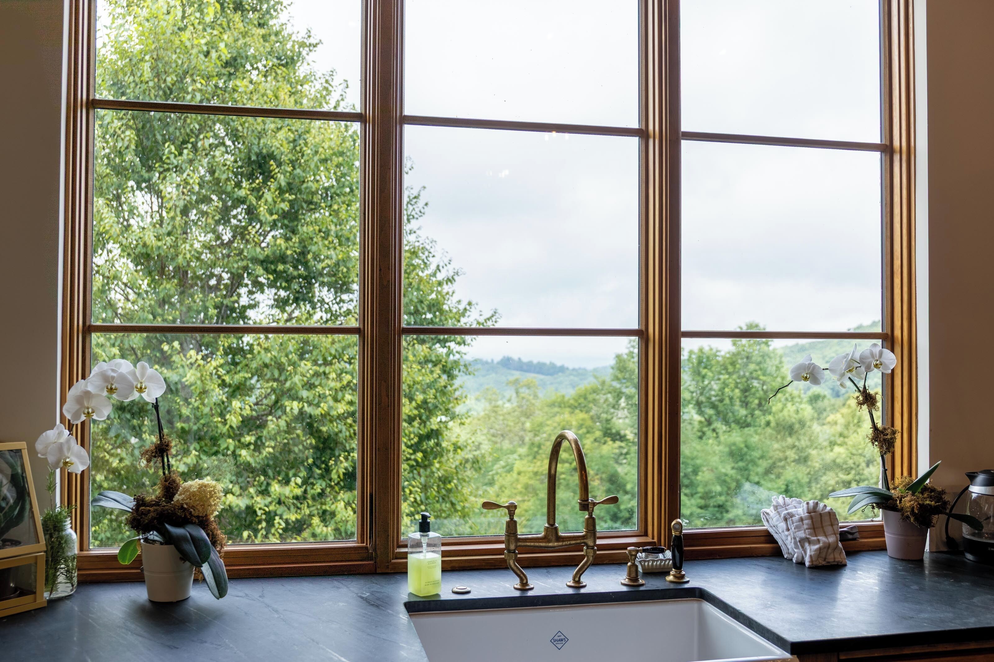 Cozinha com uma janela grande, pia e vista para o verde lá fora.