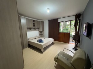 Quarto com cama, roupeiro embutido, uma cadeira e uma janela grande.