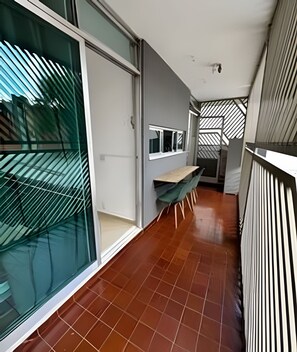 Um corredor com porta de vidro deslizante, uma pequena mesa com cadeiras e parede com padrão.