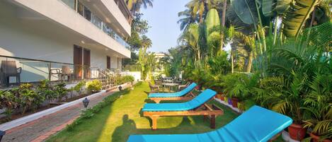 Resort com espreguiçadeiras ao ar livre, área de piscina e vegetação tropical exuberante.