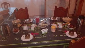 Uma mesa de jantar posta com diversos pratos, copos e uma cafeteira.