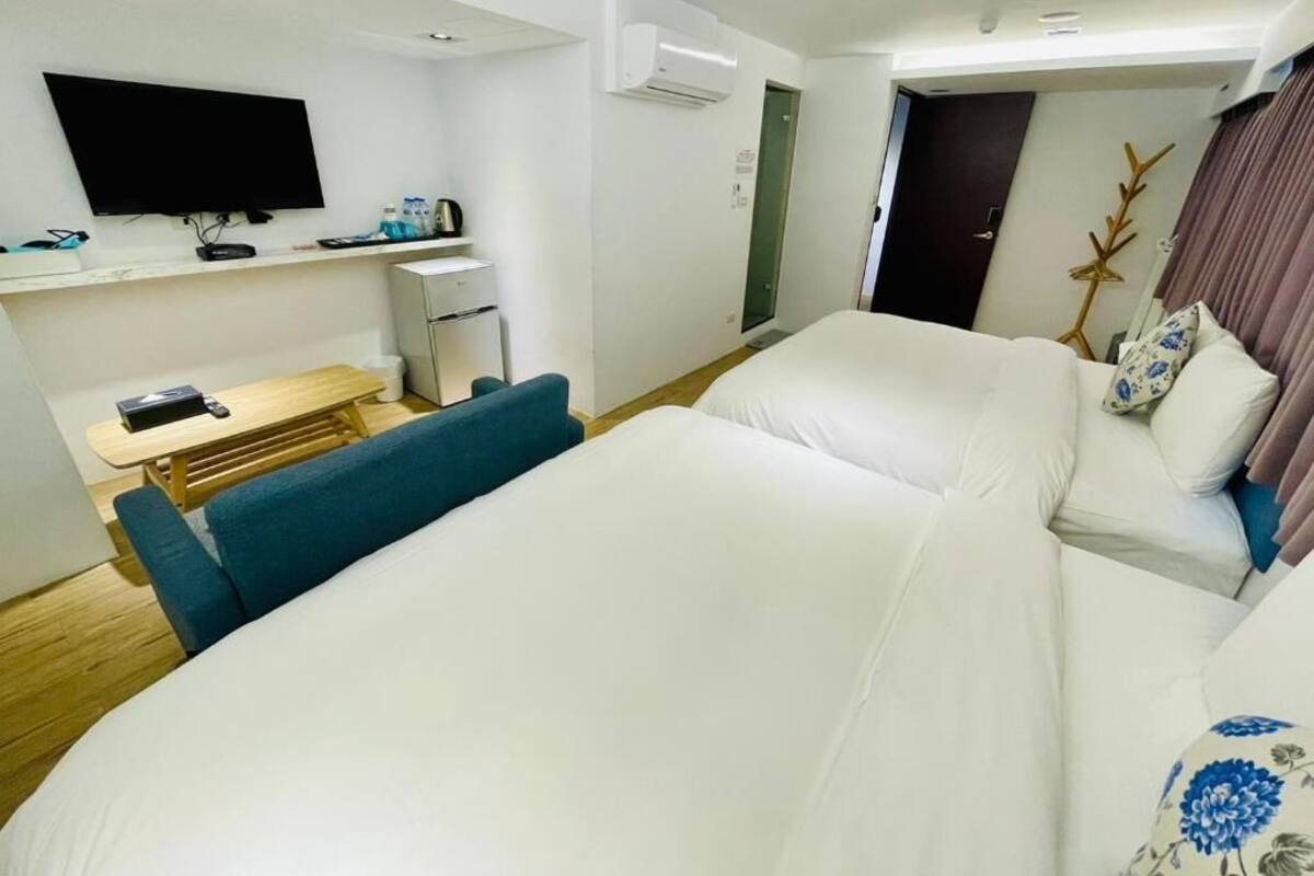 Quarto de hotel com uma cama, uma escrivaninha, uma cadeira, uma televisão e um aparelho de ar condicionado.