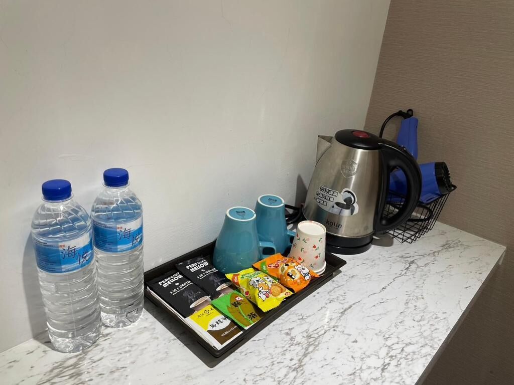 Mini bar de hotel com água engarrafada, chá e café.