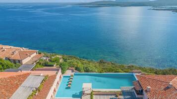 Piscina no terraço com vista clara para o mar e montanhas ao longe.