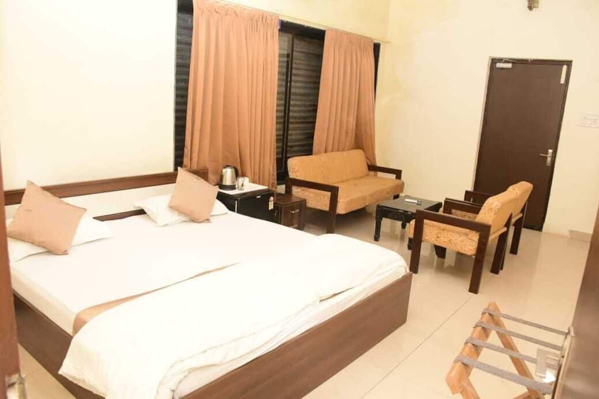 Quarto de hotel com cama, duas cadeiras, uma mesinha e uma escrivaninha com cadeira.