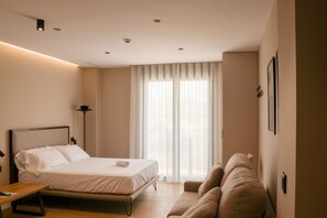 Quarto com cama, mesa de cabeceira, abajur e janela com cortinas.