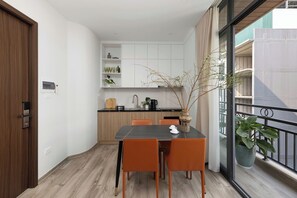 Uma cozinha moderna com armários brancos, bancada preta e área de refeições com mesa preta e cadeiras laranja.