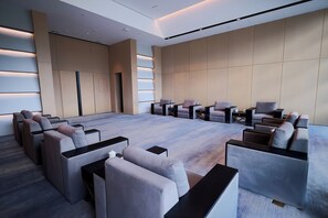 Uma sala de conferência moderna com uma mesa comprida, várias cadeiras e piso coberto por carpete.
