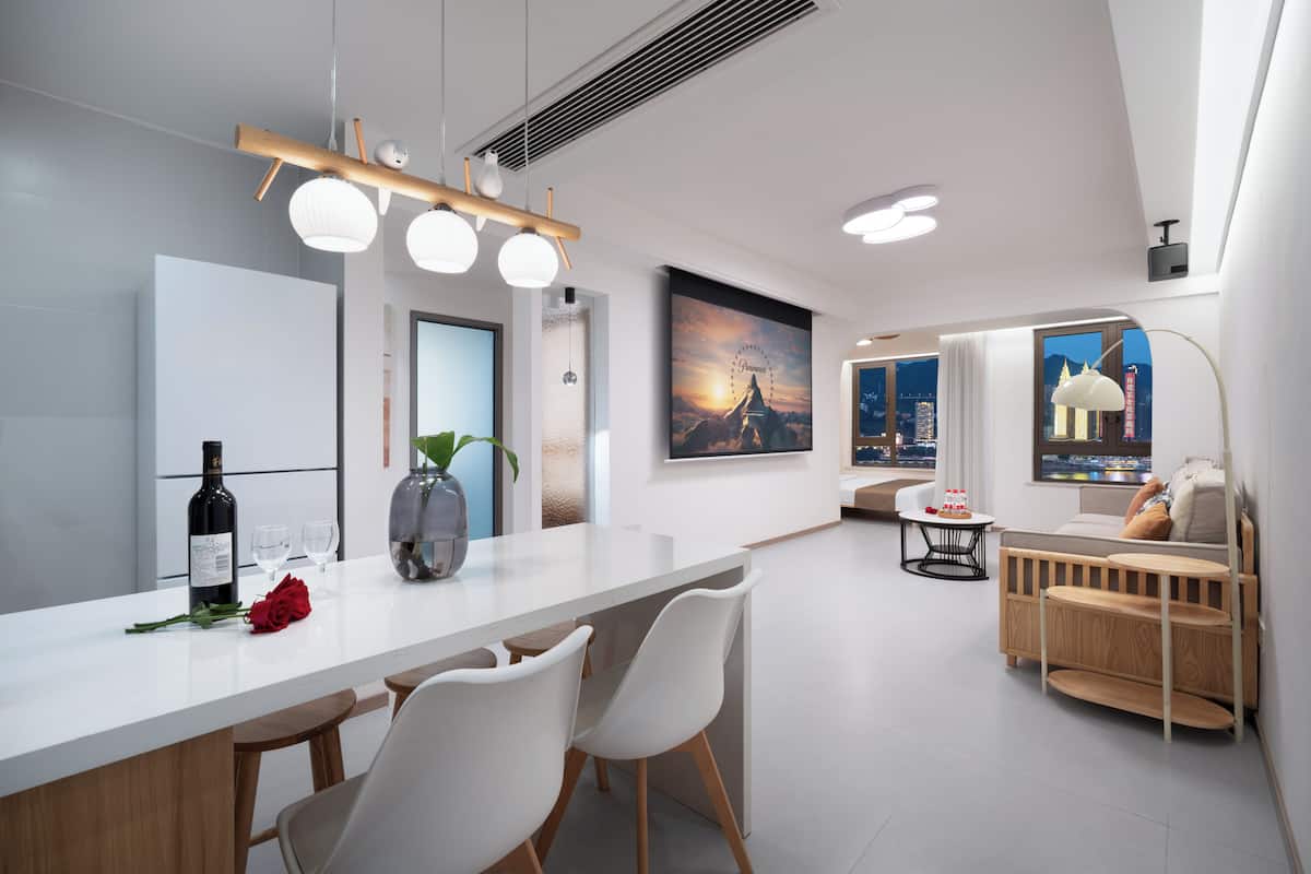 Um interior moderno com um bar branco, assentos e vista para a cidade.