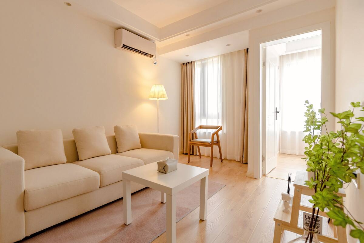 Uma sala de estar moderna com sofá, mesa de centro, luminária, poltrona e planta.